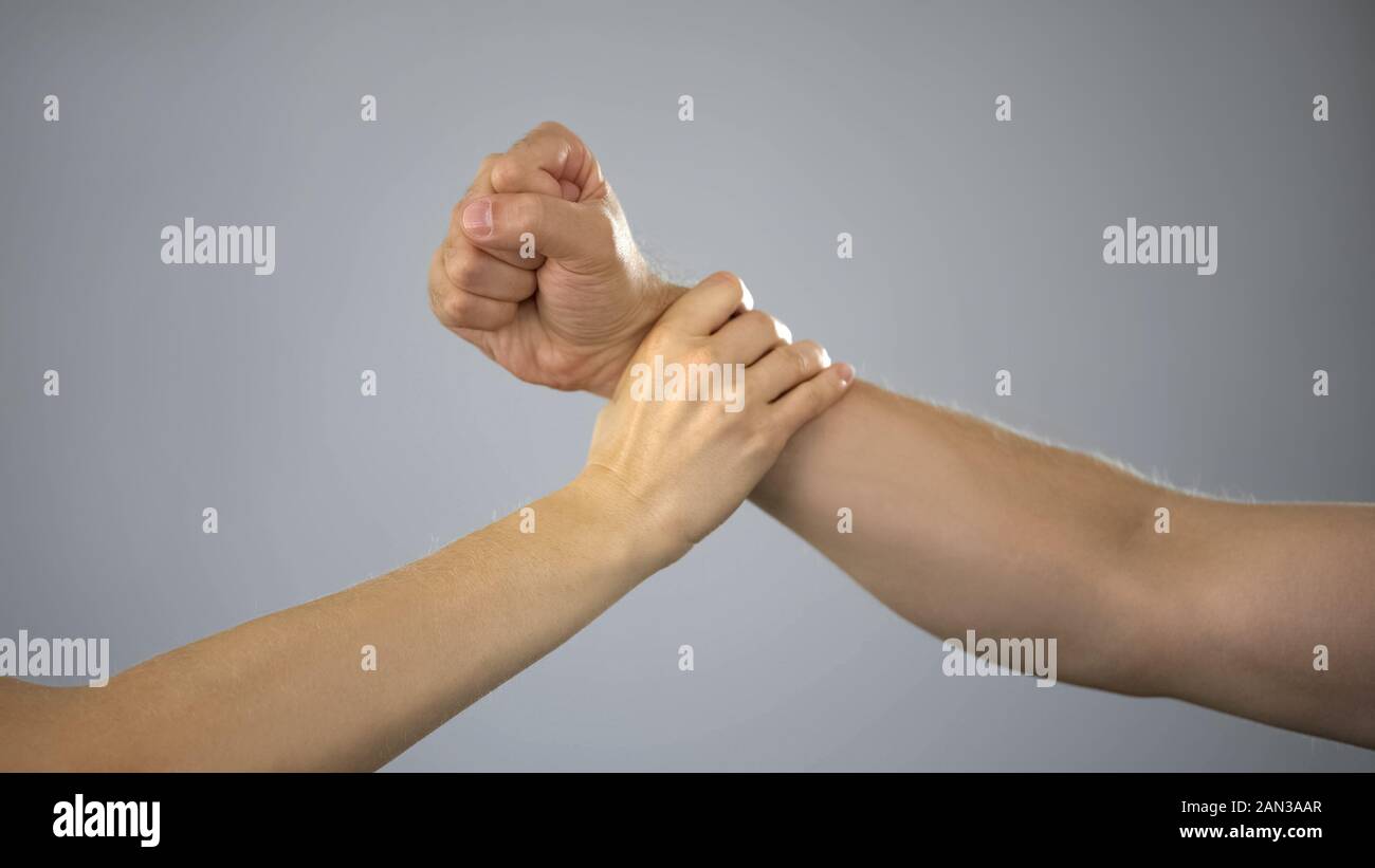 Female hand stopping male arm before attack, stop assault in family ...