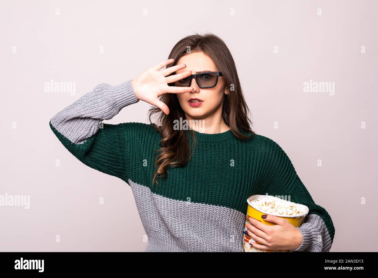 Scared young girl in 3d imax glasses covering face with palm, watching ...