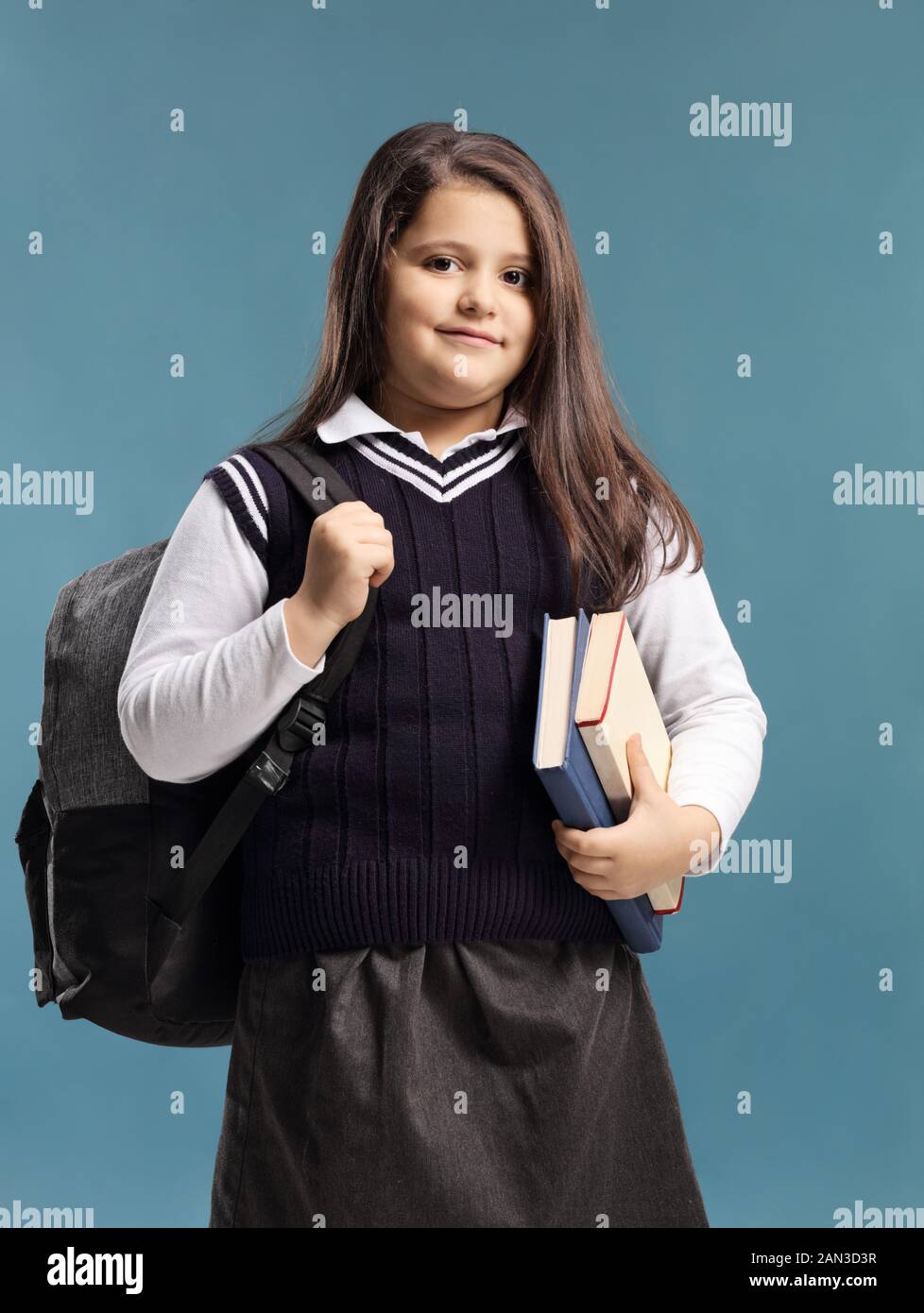 Schoolgirl in a uniform holding books over a blue background Stock ...
