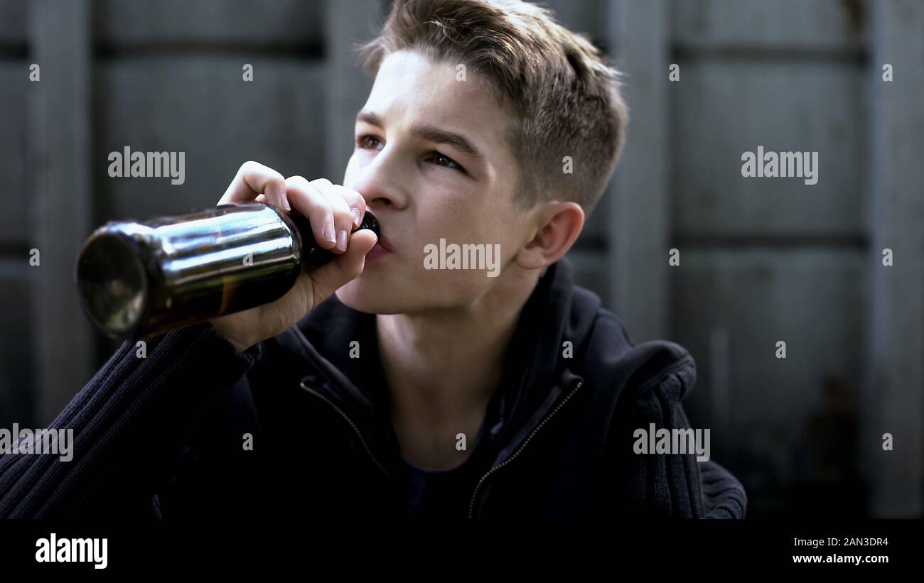 Boy drinking beer sitting in backstreet, desire to be older, first ...