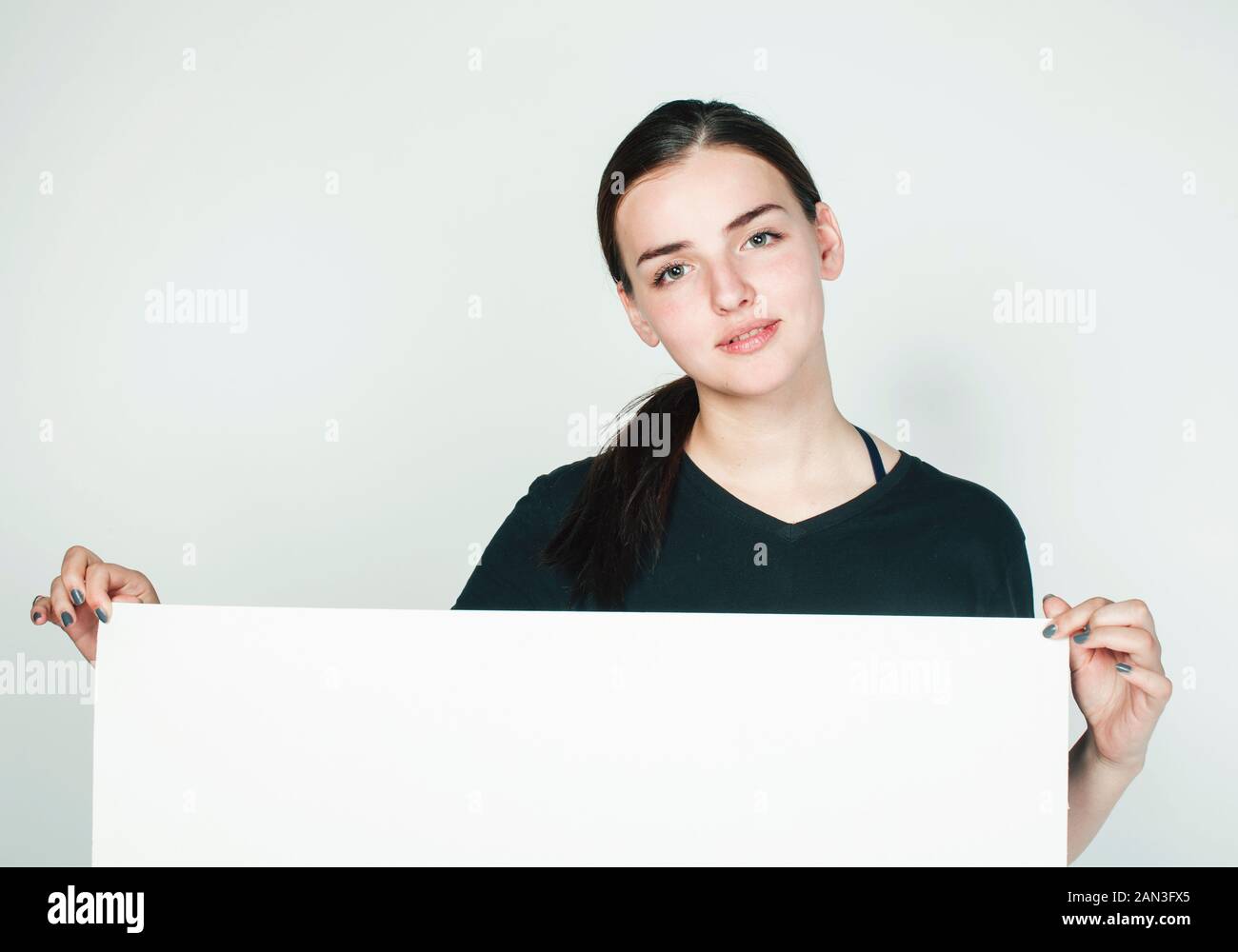 young pretty brunette girl with placard on white background wearing ...