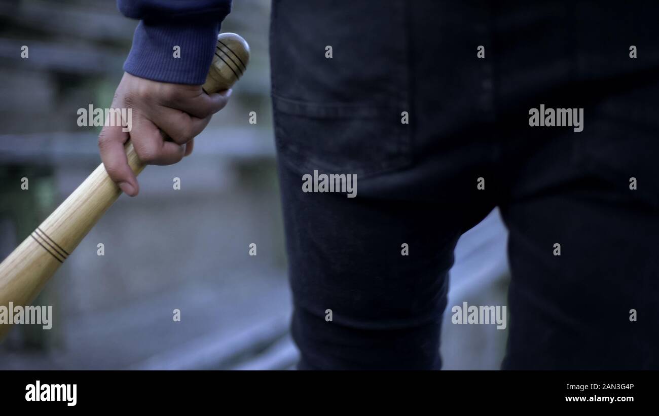 Vandalism, young man walking on stadium tribune with baseball bat ...