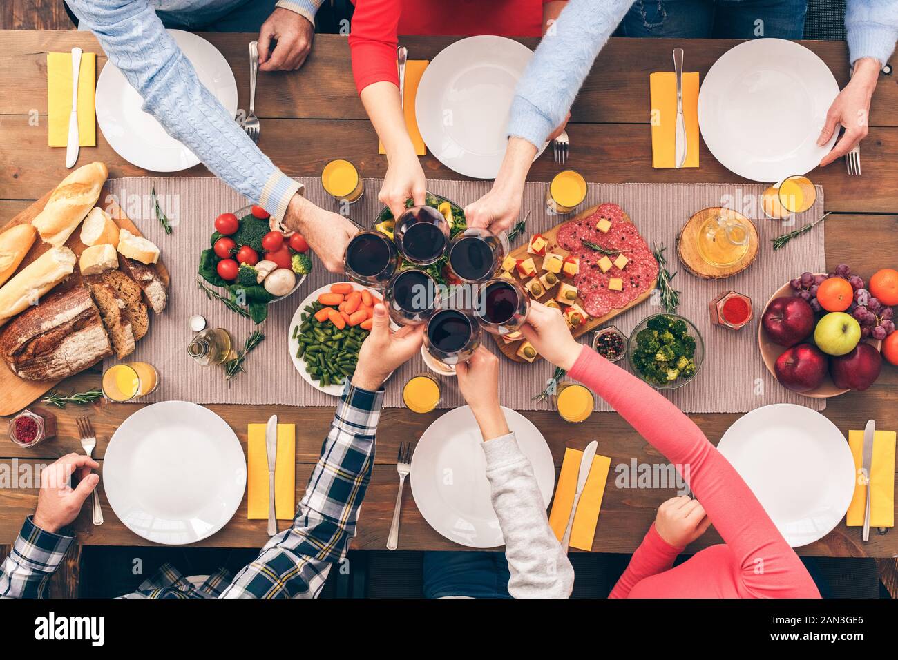 Family sitting behind table and clinking beverage glasses Stock Photo ...
