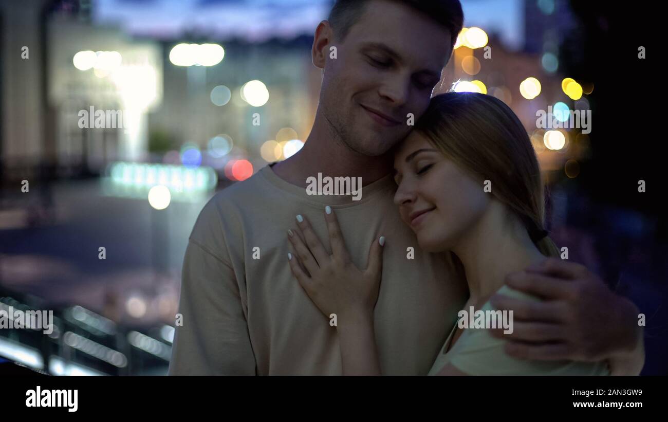 Lovely couple tenderly hugging against night city background, romantic ...
