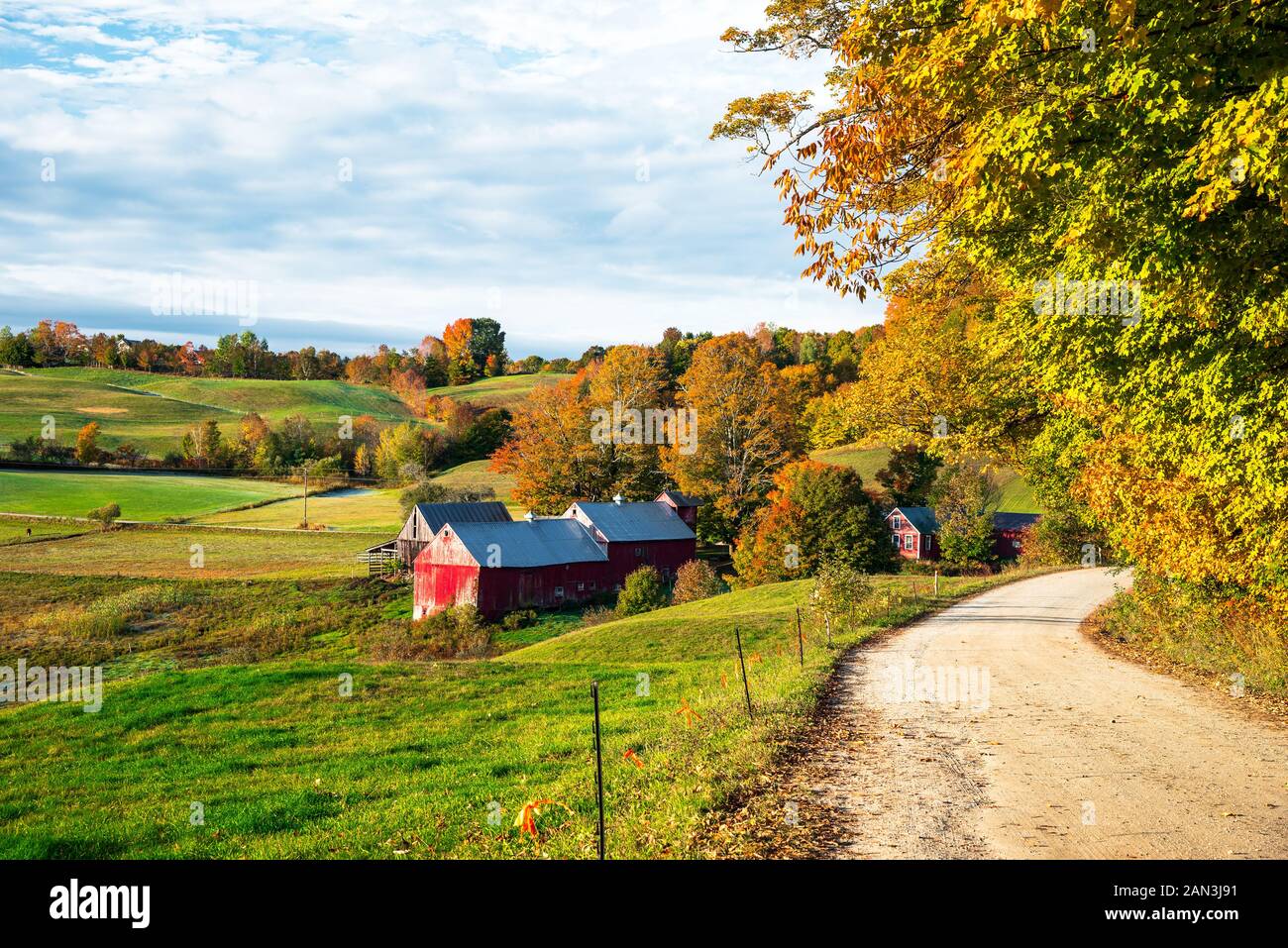 Traditional farm along a gravel road in a rolling rural landscape in ...