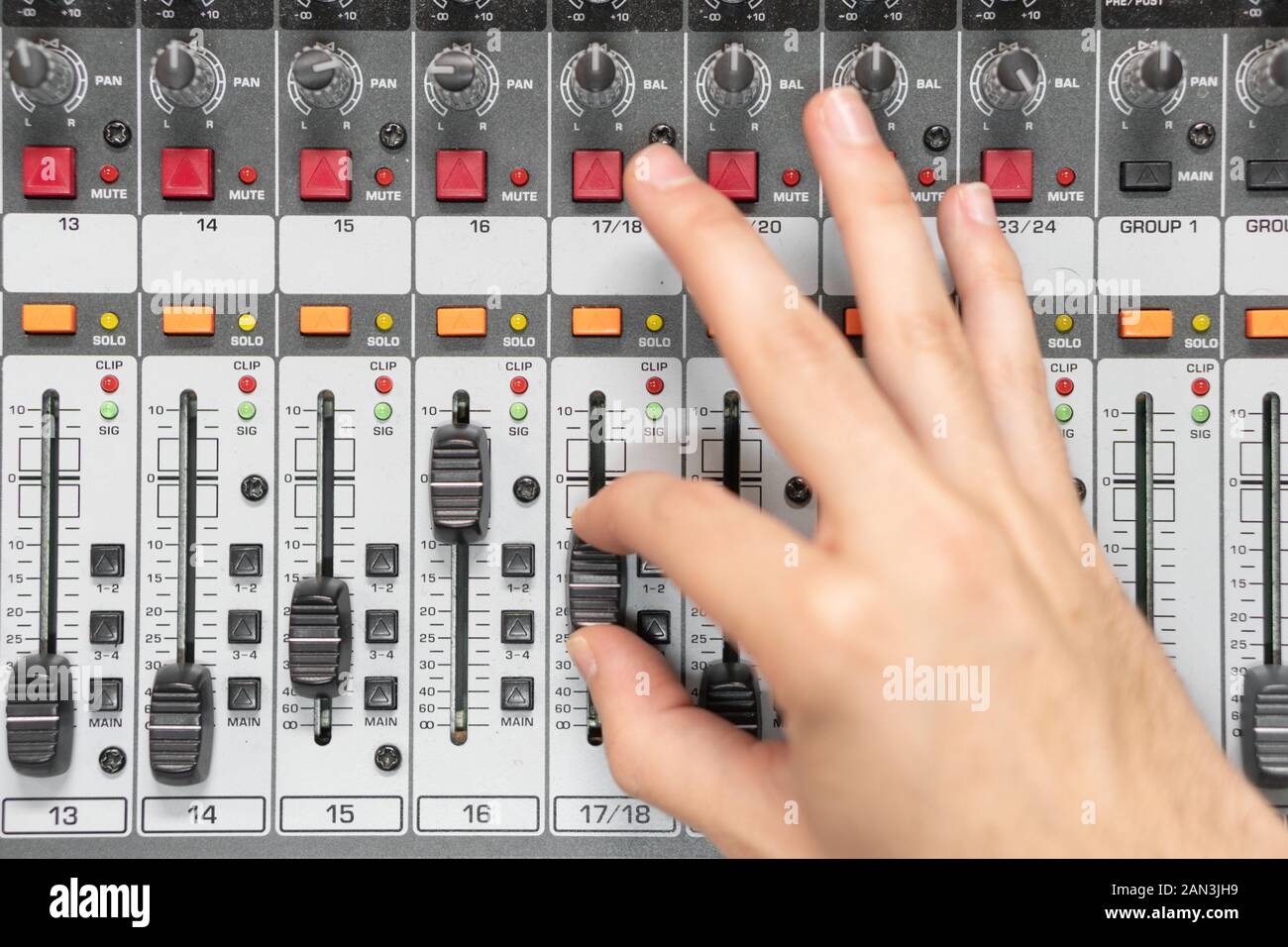 Close-up of a mixing console, hand equalizing audio channels ...