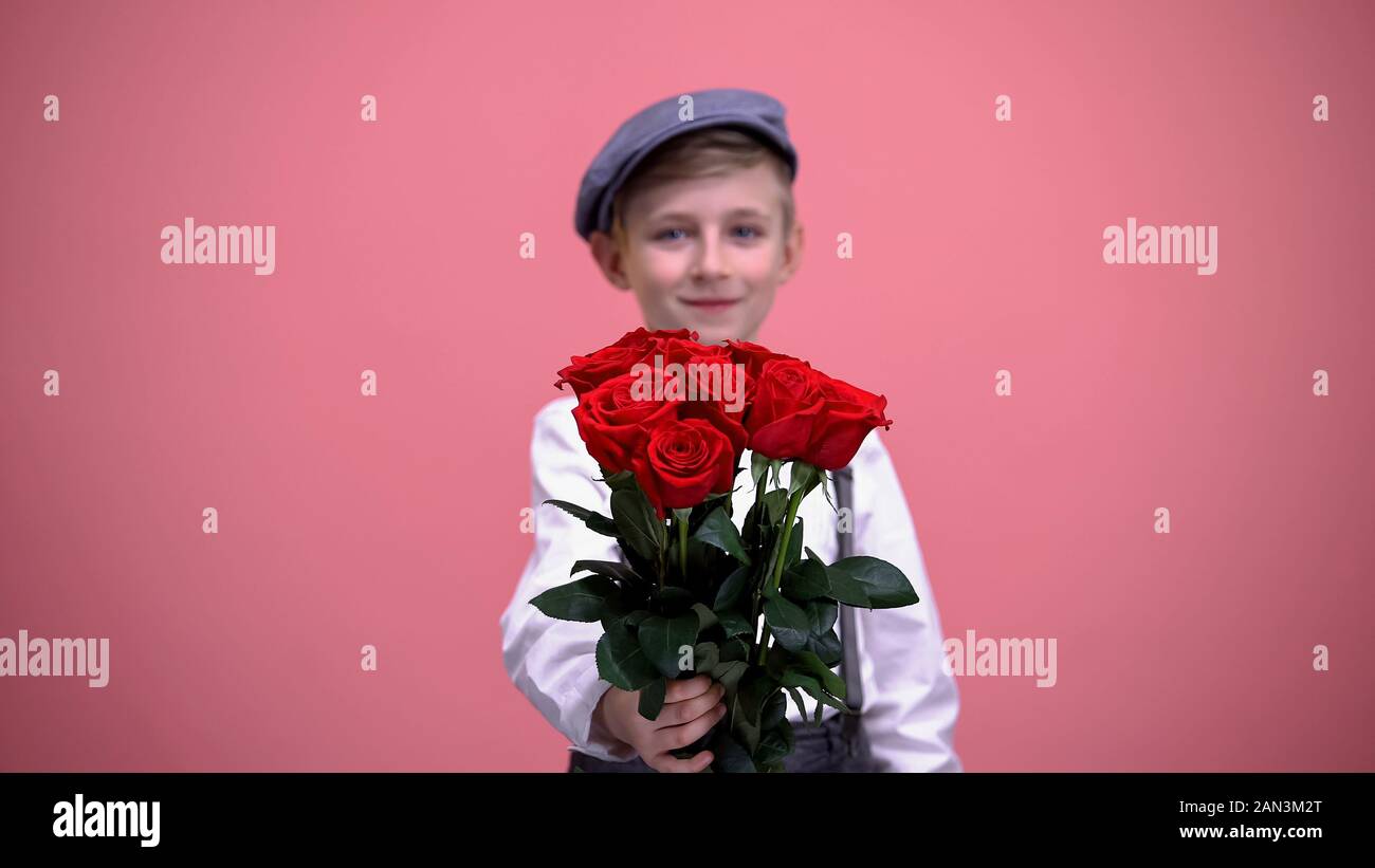 Little handsome boy showing bouquet of red roses into camera ...