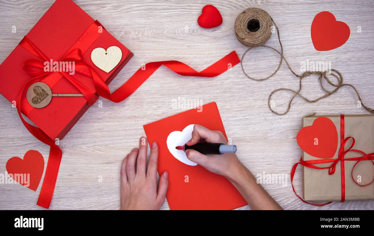 Hand writing love word on greeting card lying on table with craft gift ...