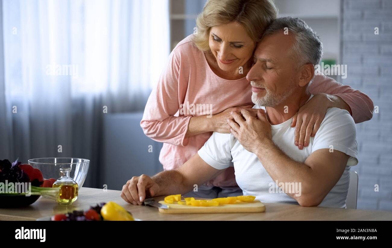 Happy retired couple hugging at home kitchen, love and harmony, cooking ...