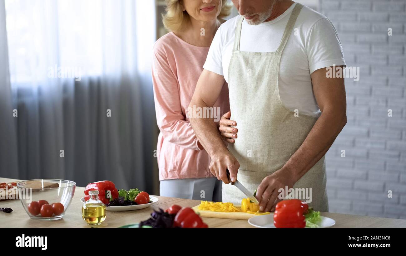 Retired male cooking salad, caring wife hugging husband, family support ...