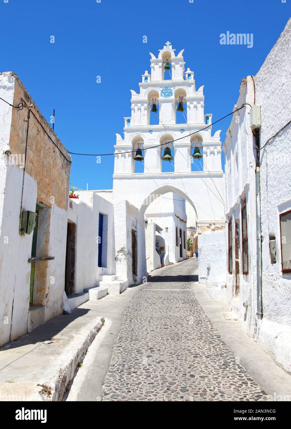 A typical cobblestone street with an arched bell tower in the ...