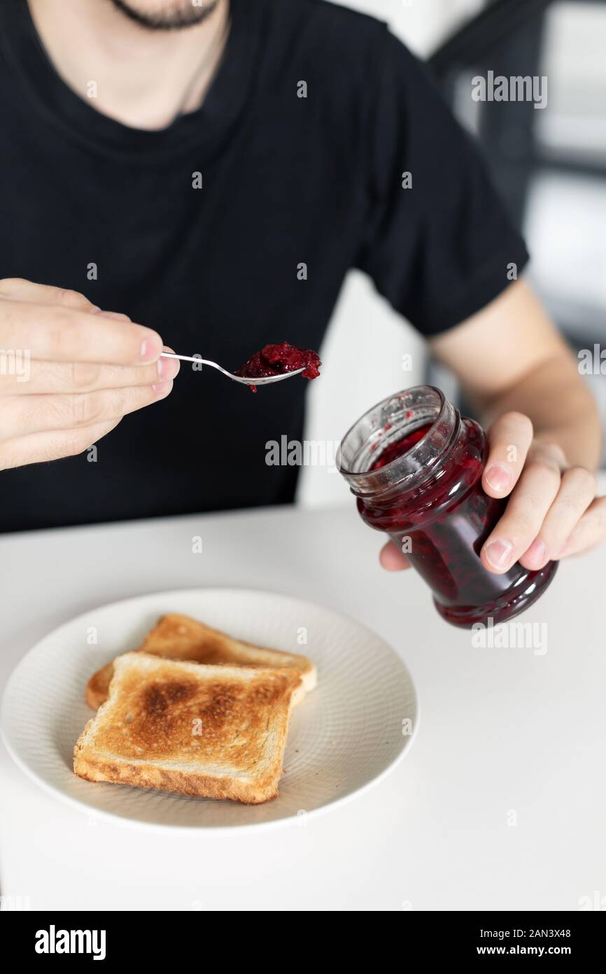 The guy has breakfast with toast with jam Stock Photo - Alamy