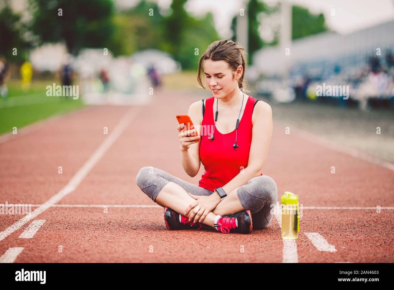 beautiful fitness girl uses smartphone at stadium after workout. Sports ...