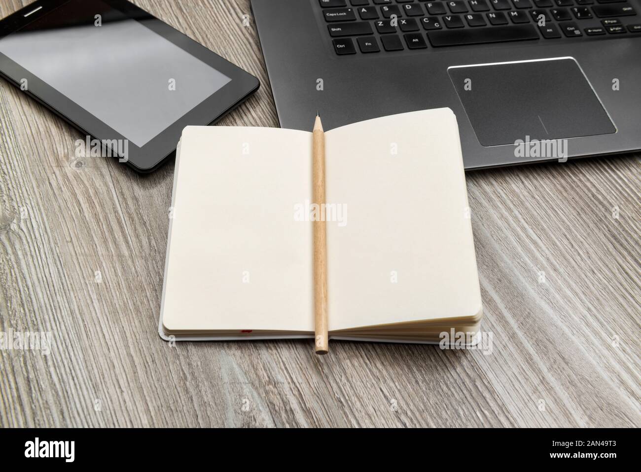 Opened blank notepad and pen at a working place with laptop and a ...