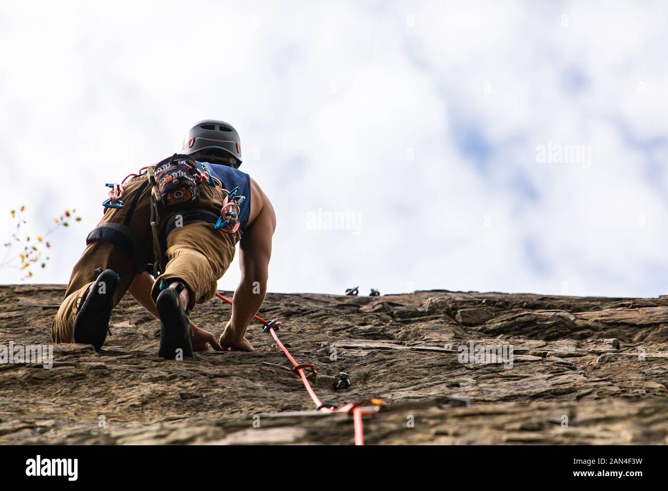 A low angle view of a male rock climber near the summit of a natural ...