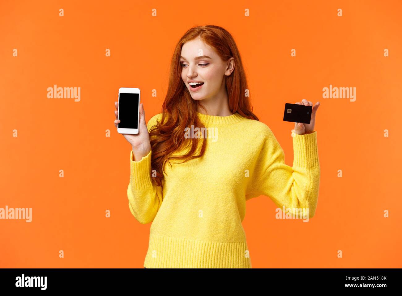 Enthusiastic pretty modern redhead girl advertising mobile banking ...