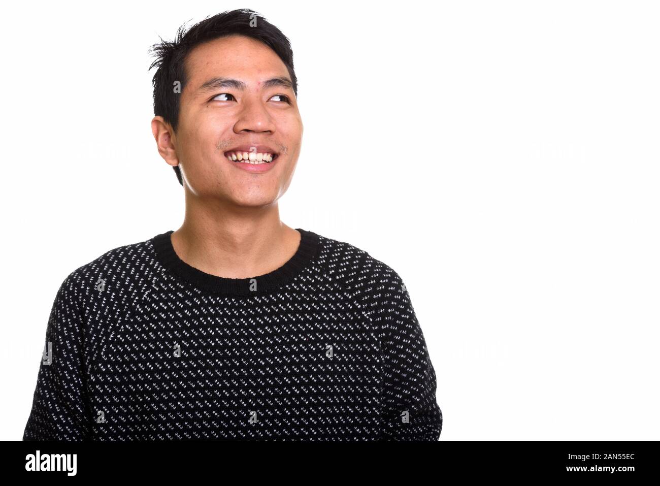 Studio shot of young happy Asian man smiling while thinking Stock Photo ...
