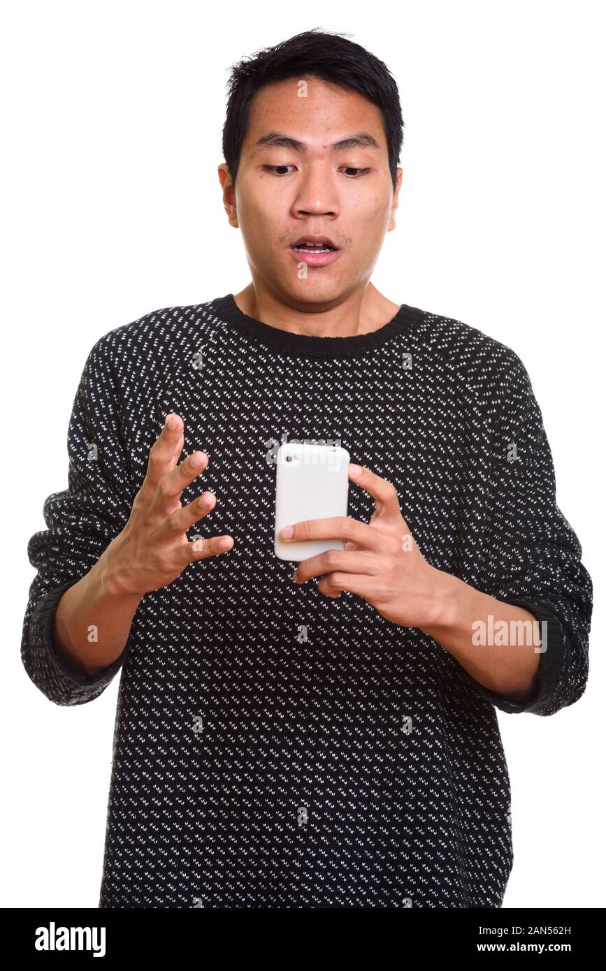 Studio shot of young Asian man looking shocked while holding mob Stock ...