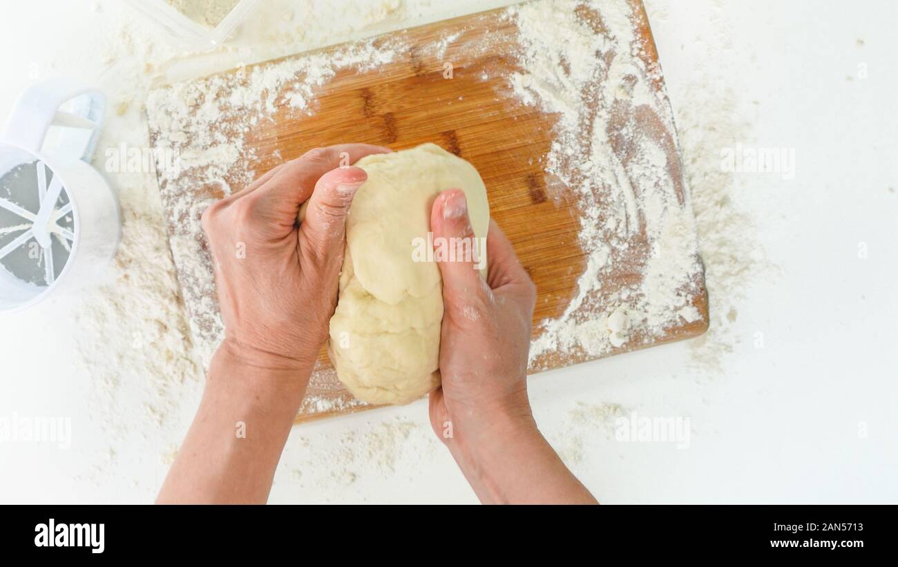 Dough preparation. Woman hands kneading dough in flour on a wooden ...