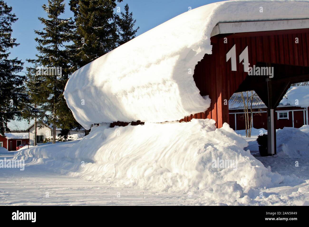 The heavy snow load slowly flows downwards from the roof of the carport ...