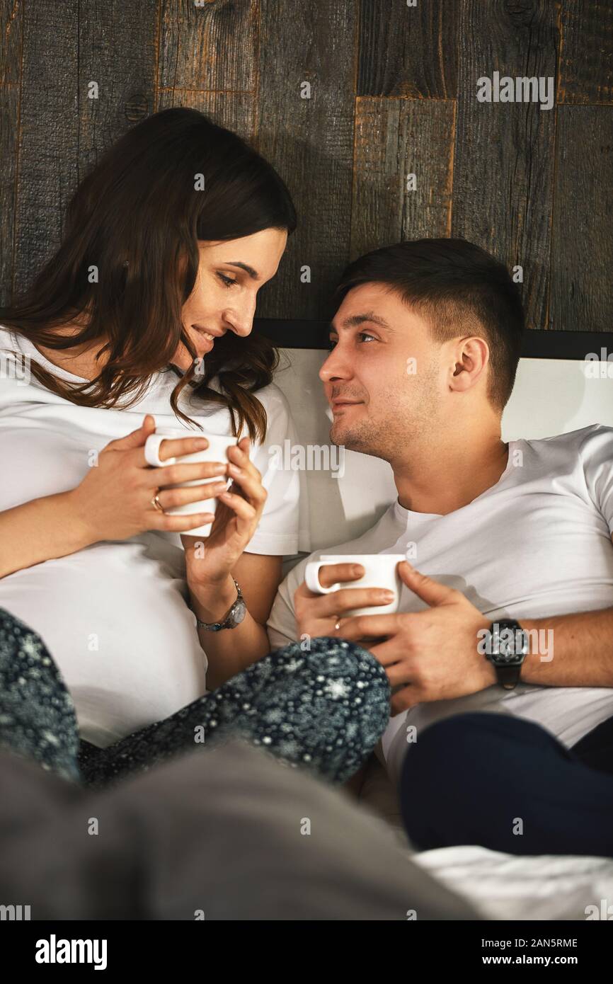 A young married couple awaiting a baby. Beautiful couple lying in the ...