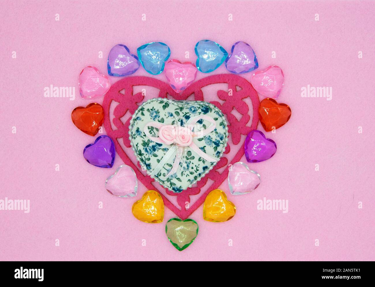 Bright heart made of felt and colored glass and a gift box on a pink ...