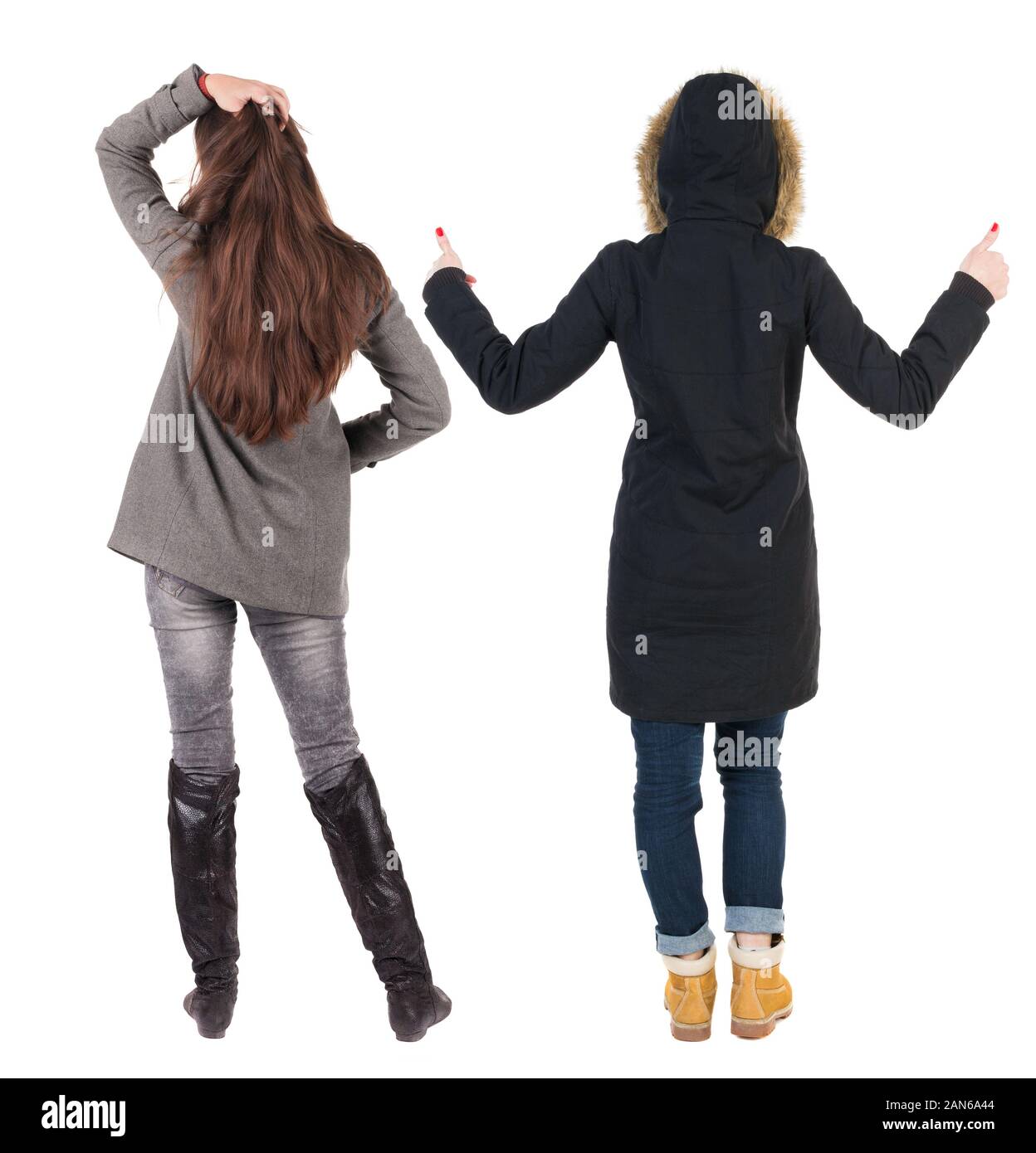 Back view of two young girl in winter jacket showing thumb up. Rear ...