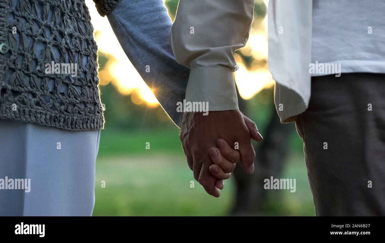 Senior man and woman holding hands and enjoying date in park ...