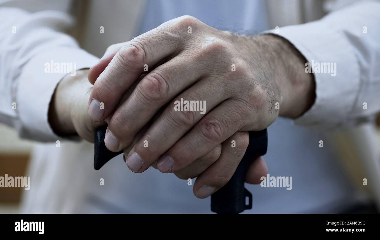 Elderly male putting hands on walking stick, retirement and disability ...