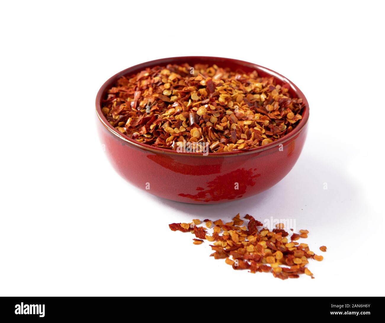 head on shot of Hot chilli flakes in a red colored bowl isolated on a ...