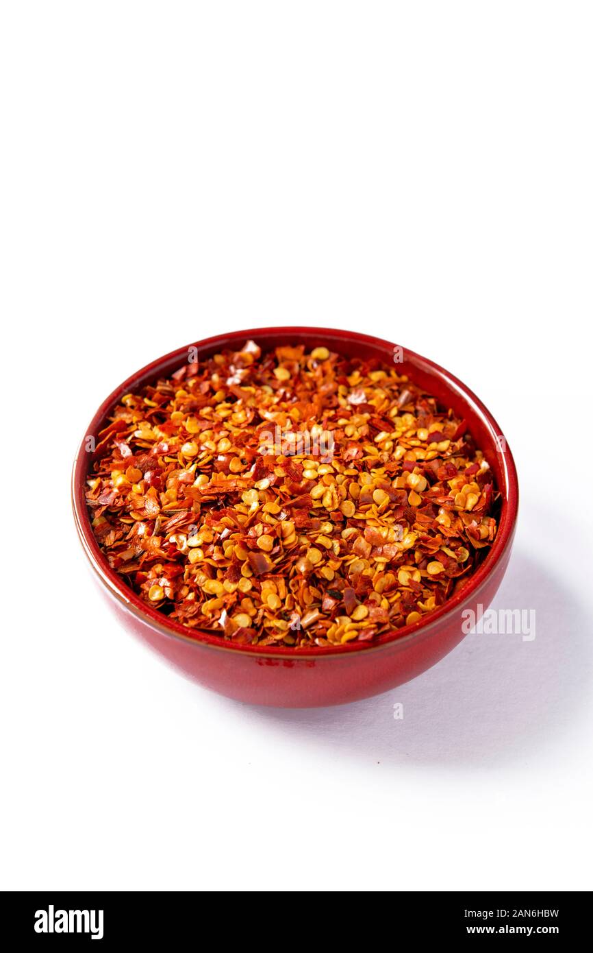 Hot chilli flakes in a round red colored bowl isolated on a white ...
