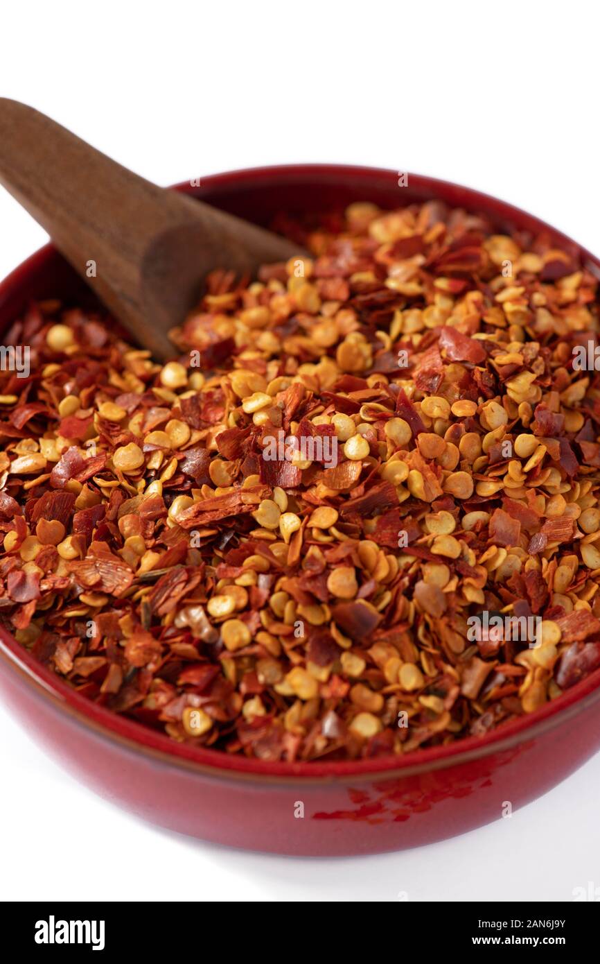 macro shot of Hot chilli flakes in a red colored bowl with spoon ...