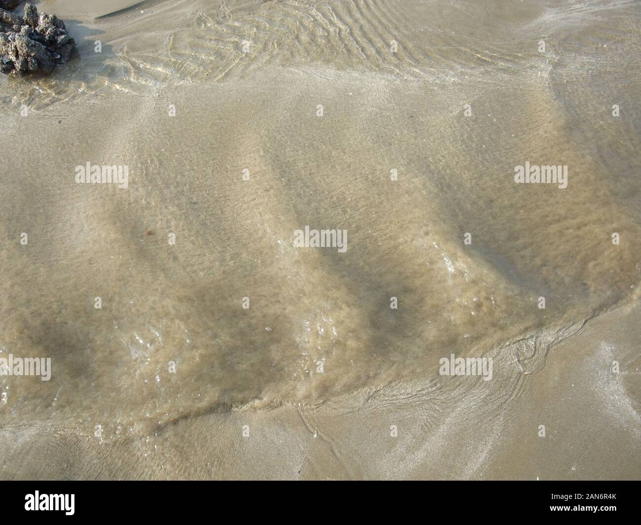 Water flowing over sand forming pattern Stock Photo - Alamy