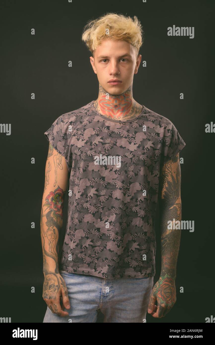 Young handsome rebellious man with blond hair against black background ...