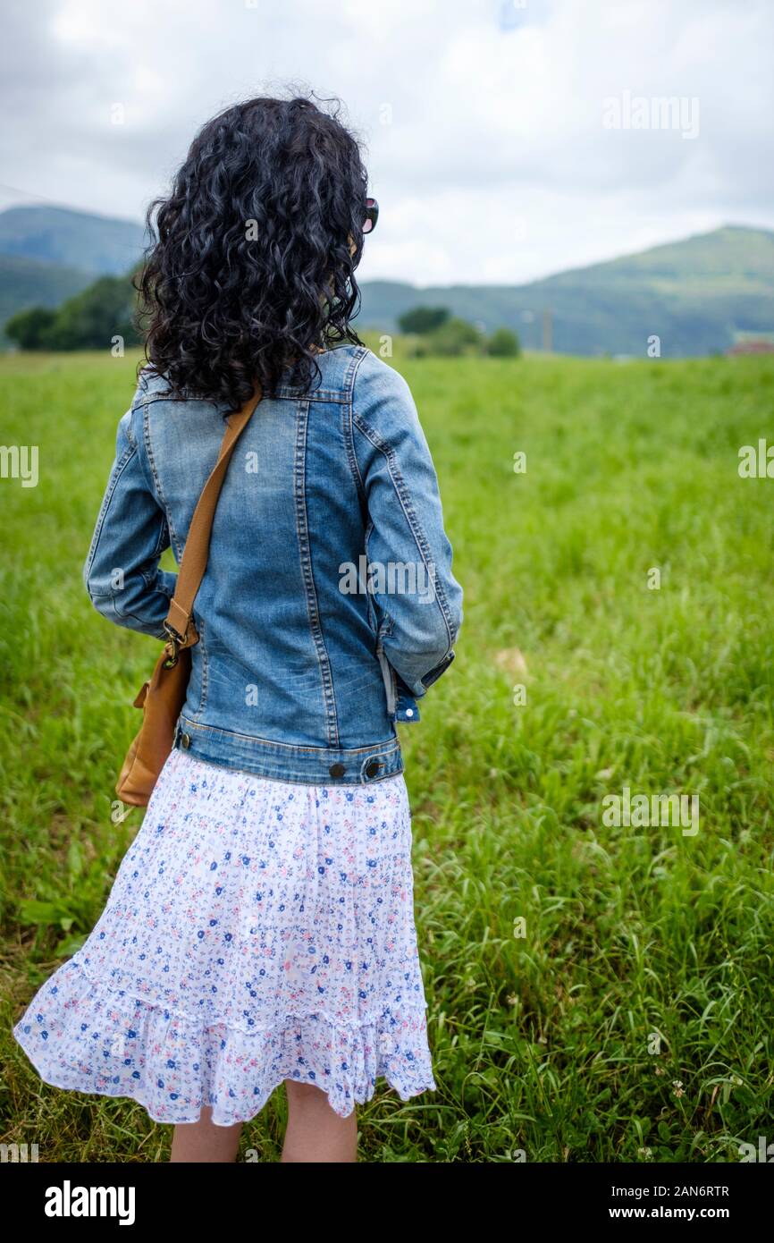 Woman from behind standing and looking at the countryside Stock Photo ...