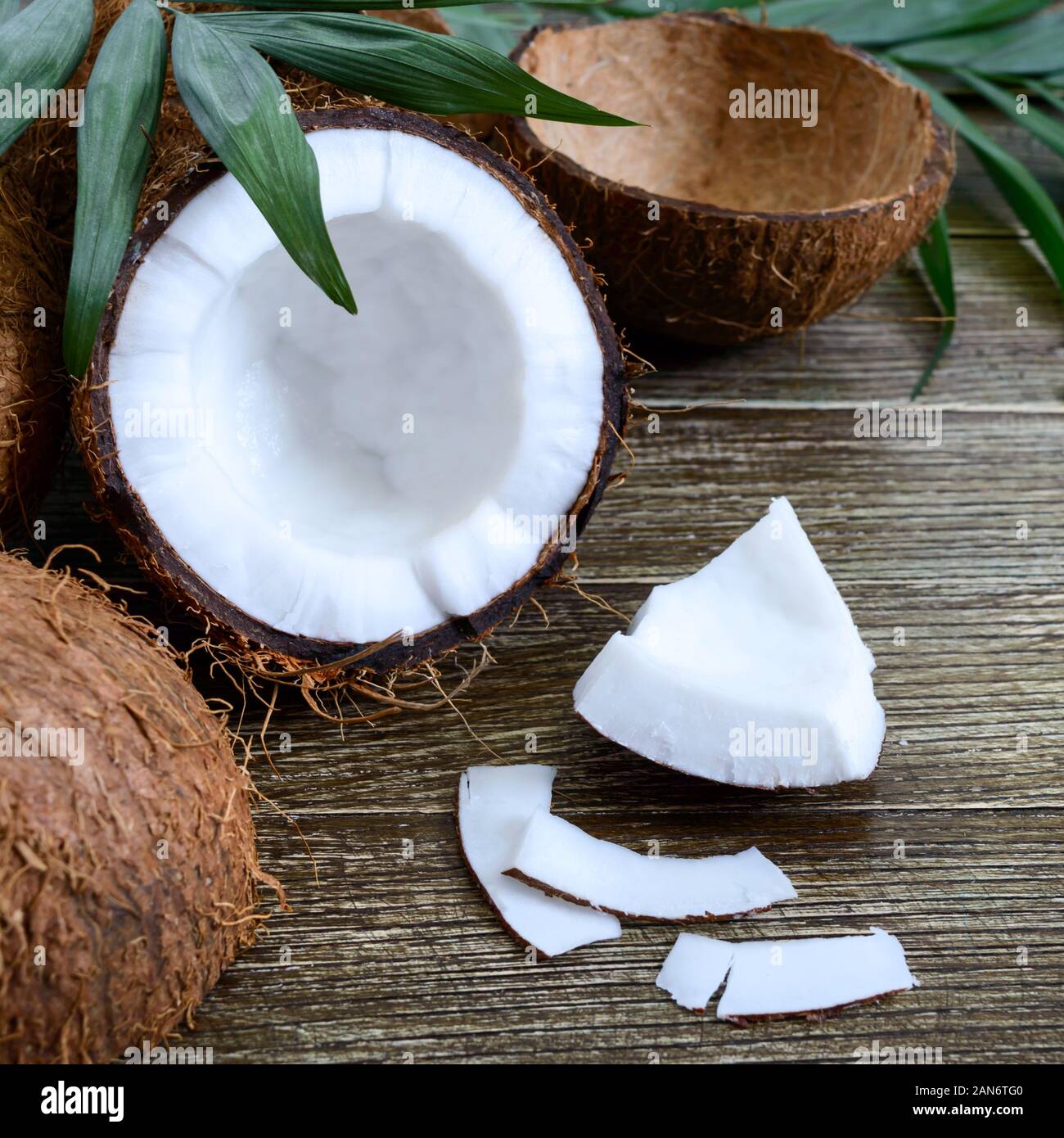 Coconut. Whole coconut, shell, coconut flakes and green leaves on a ...