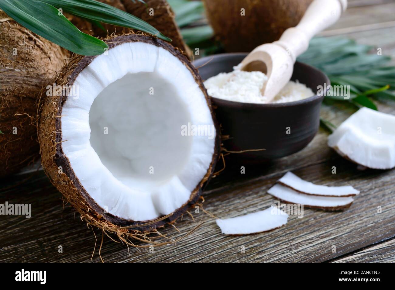 Coconut. Whole coconut, shell, coconut flakes and green leaves on a ...