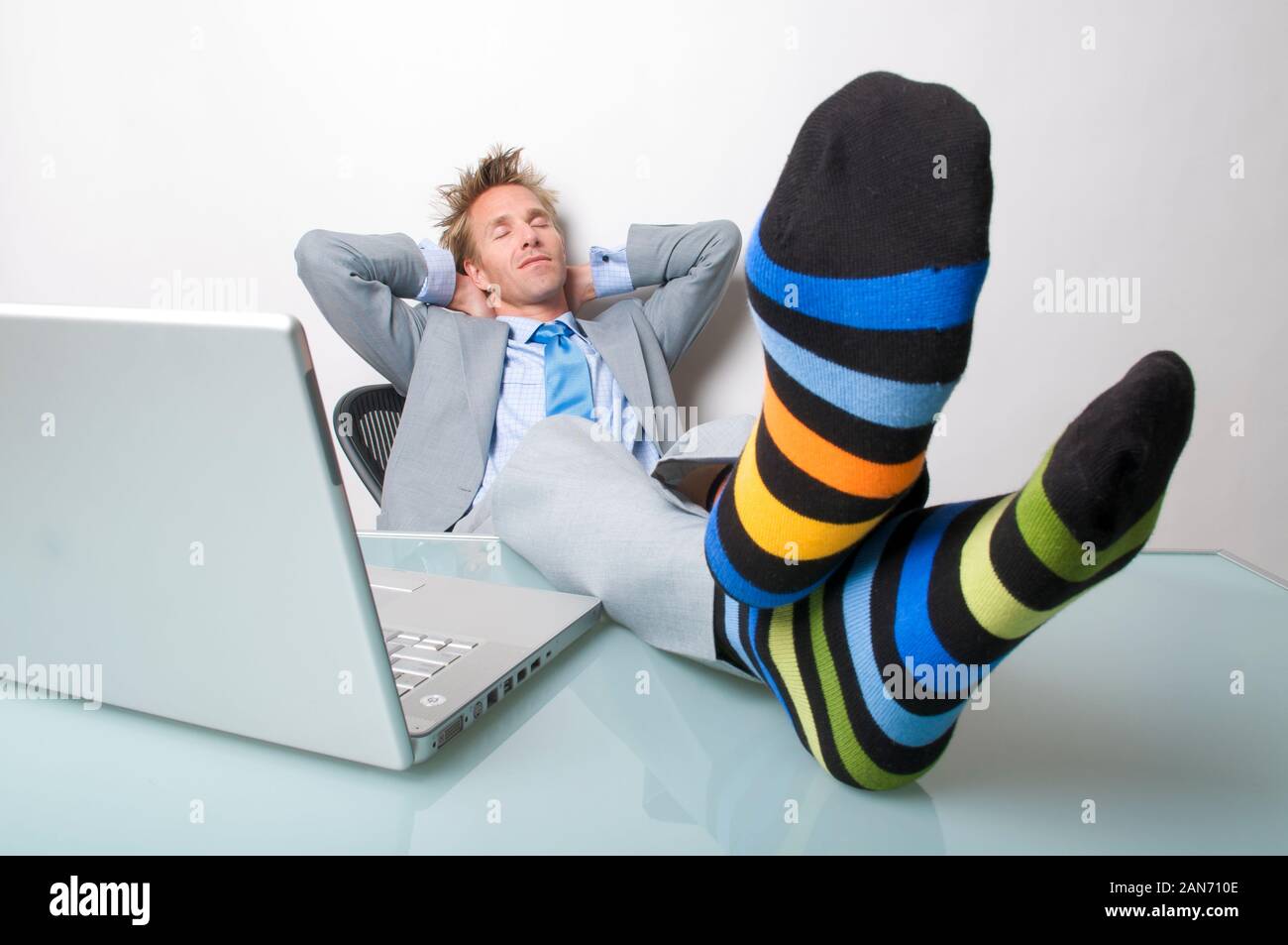 Sleepy businessman relaxing with his socks up on the desk next to his ...