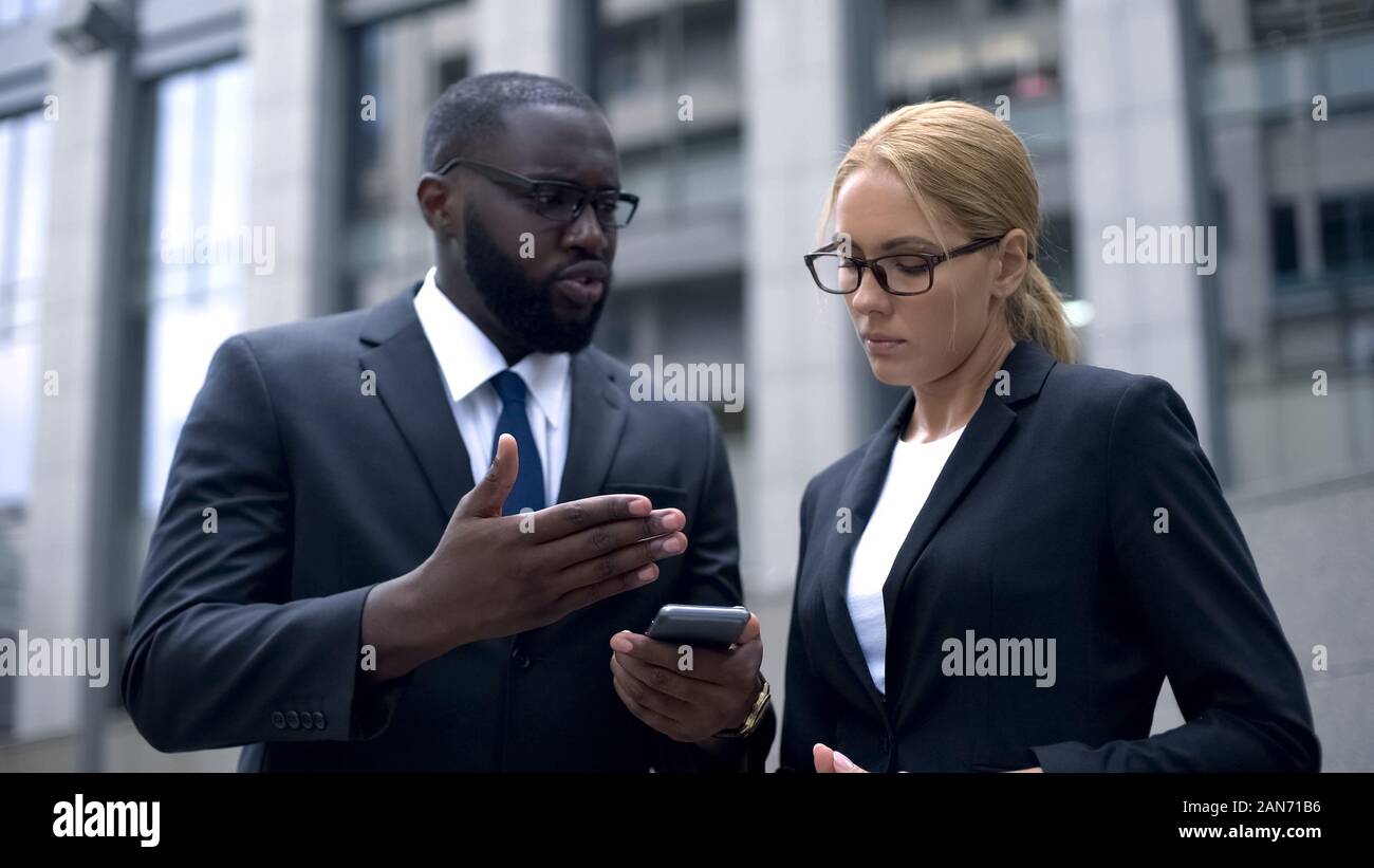 Business people holding smartphone, dissatisfied with inappropriate ...