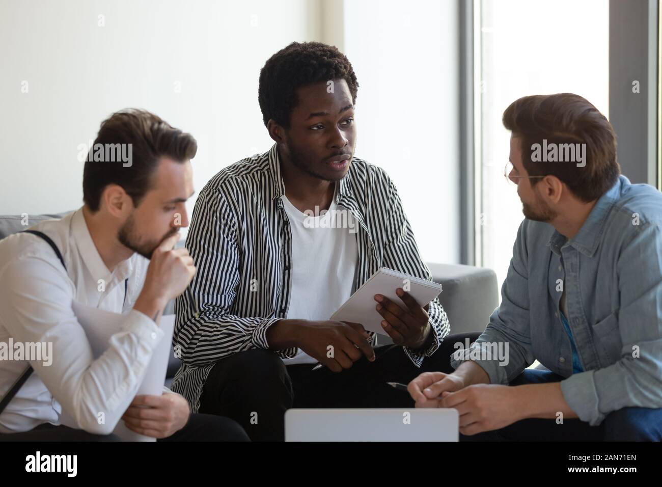 Focused multiracial men brainstorming discussing business project Stock ...