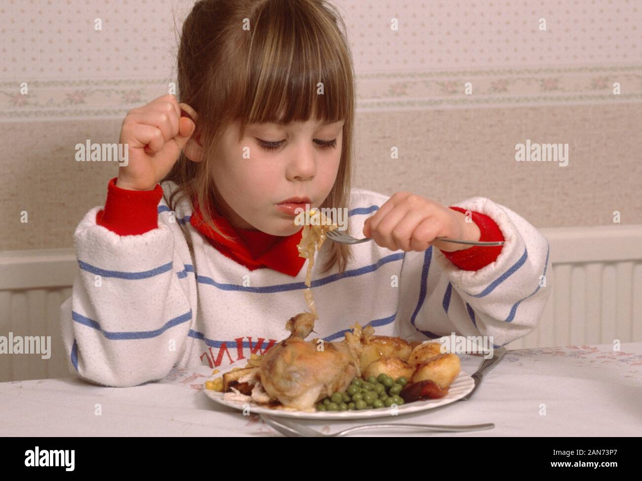 little girl eating a cooked meal that is too large for her Stock Photo ...