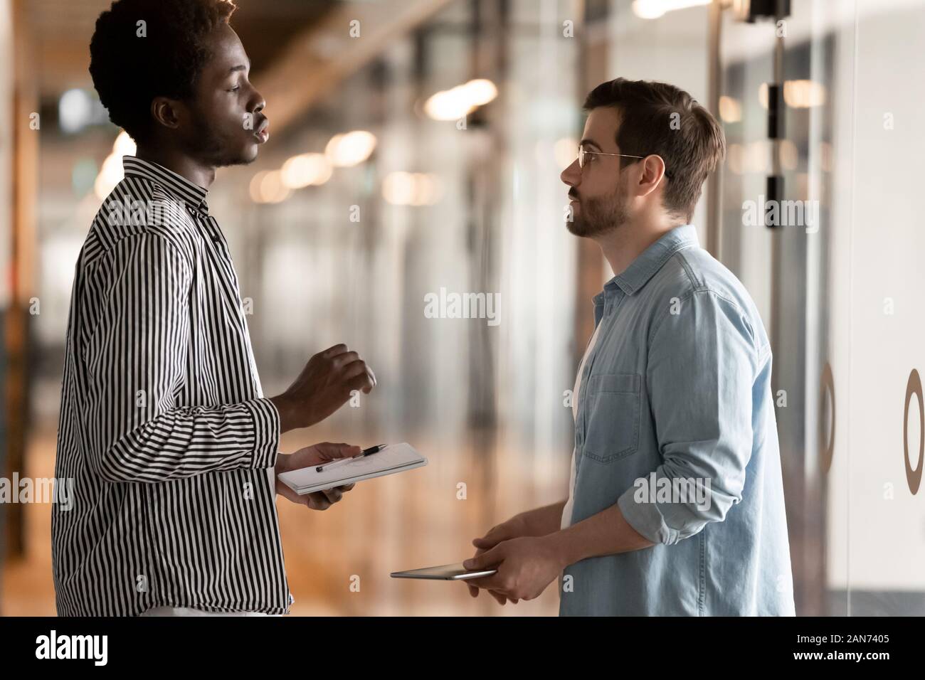 Multiethnic male colleagues talk in office hallway Stock Photo - Alamy