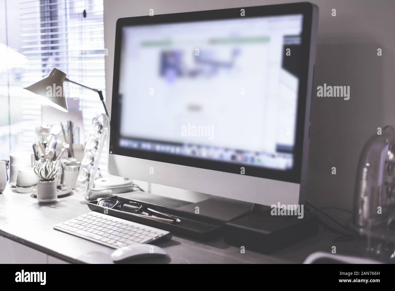 Blurred large computer screen on a home office desk interior eith work ...
