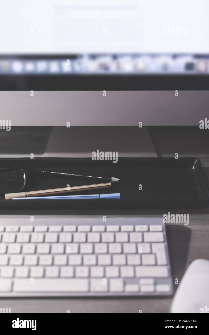 Blurred large computer screen on a home office desk interior eith work ...