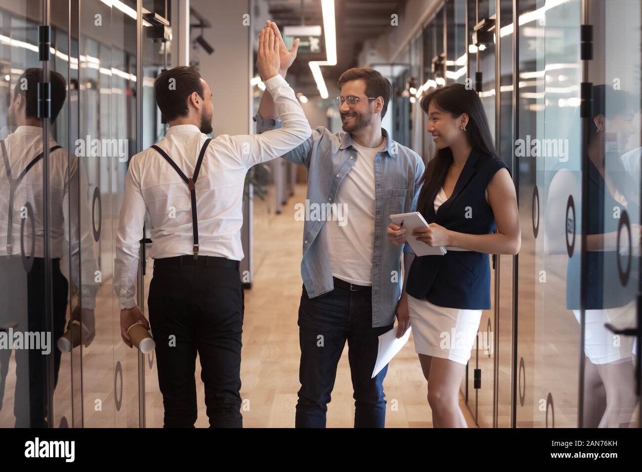Smiling millennial colleagues give high five meeting in hallway Stock ...