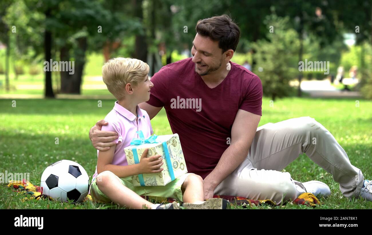 Father giving present to son for good grades at school, encourages to ...