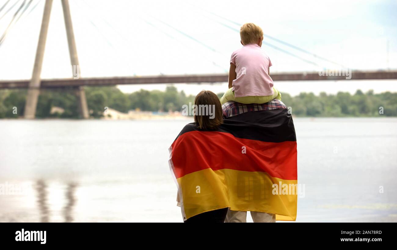 Family wrapped in German flag looking at bridge, immigration ...