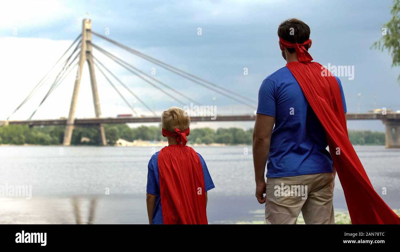 Father and son in superman costumes looking at bridge, dads support ...