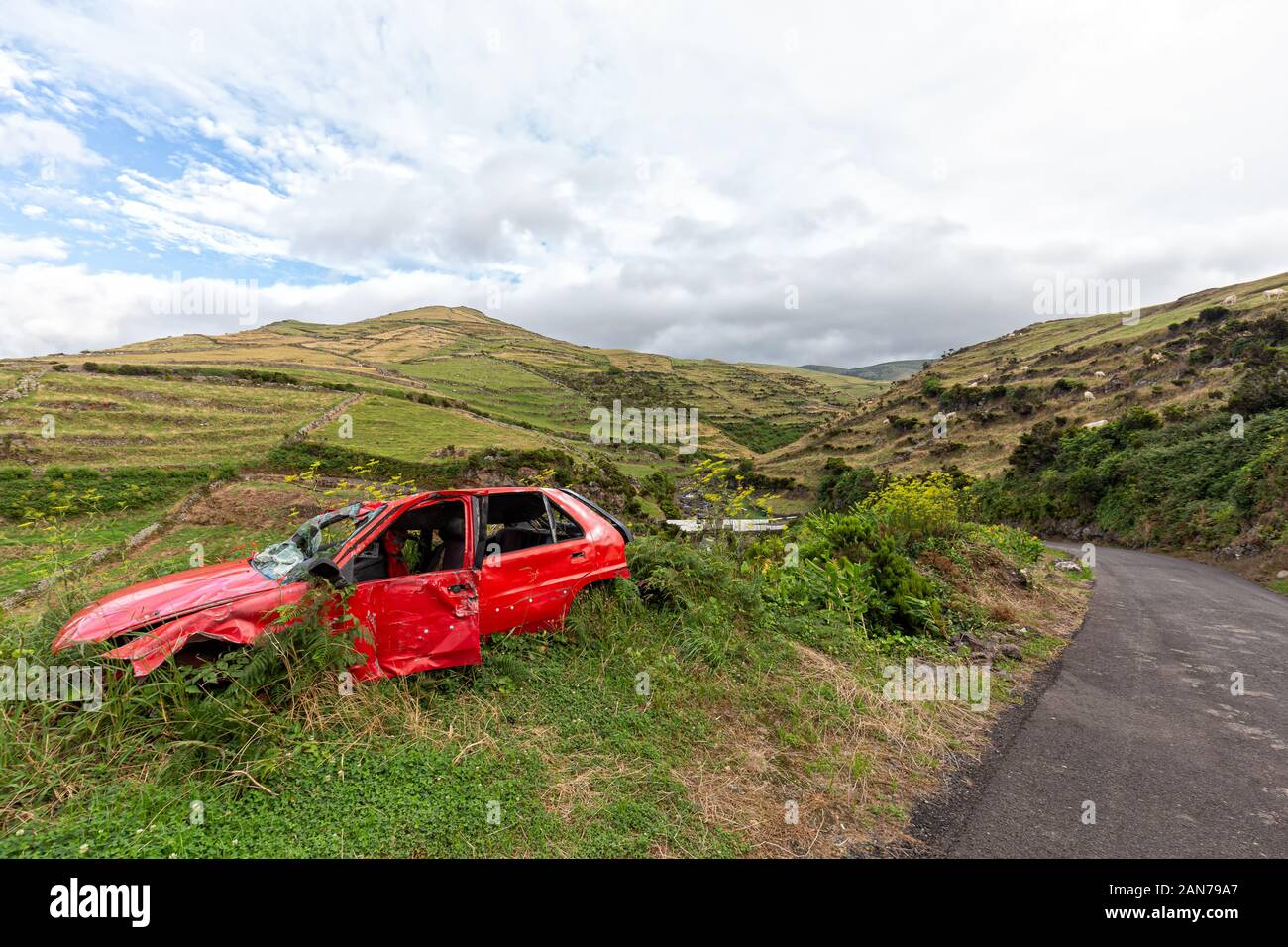 An abandoned smashed red car on the side of the road in rural Flores ...