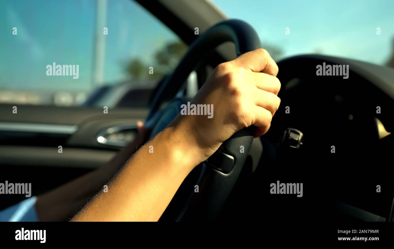 Teenagers hands holding black steering wheel, girl driving car ...